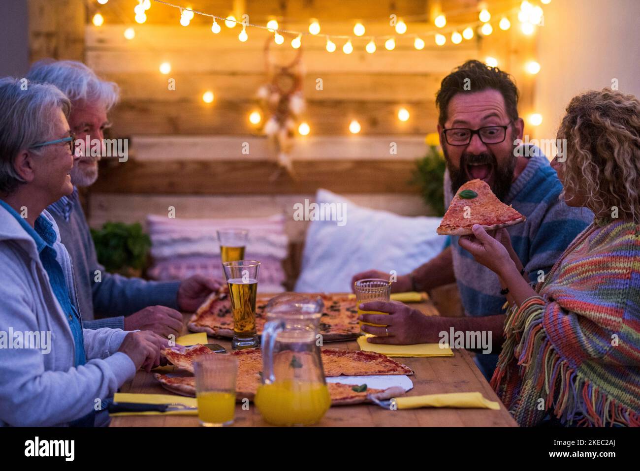 group of four people eating together at home or restaurant with pizzas ...