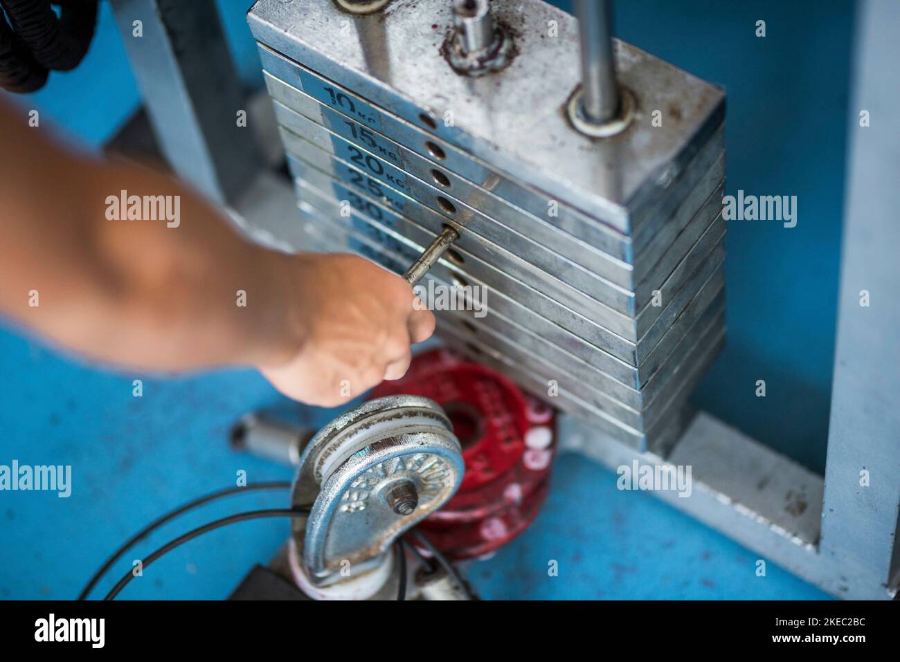 close up of hand of man or woman changing a weight on a machine in the ...