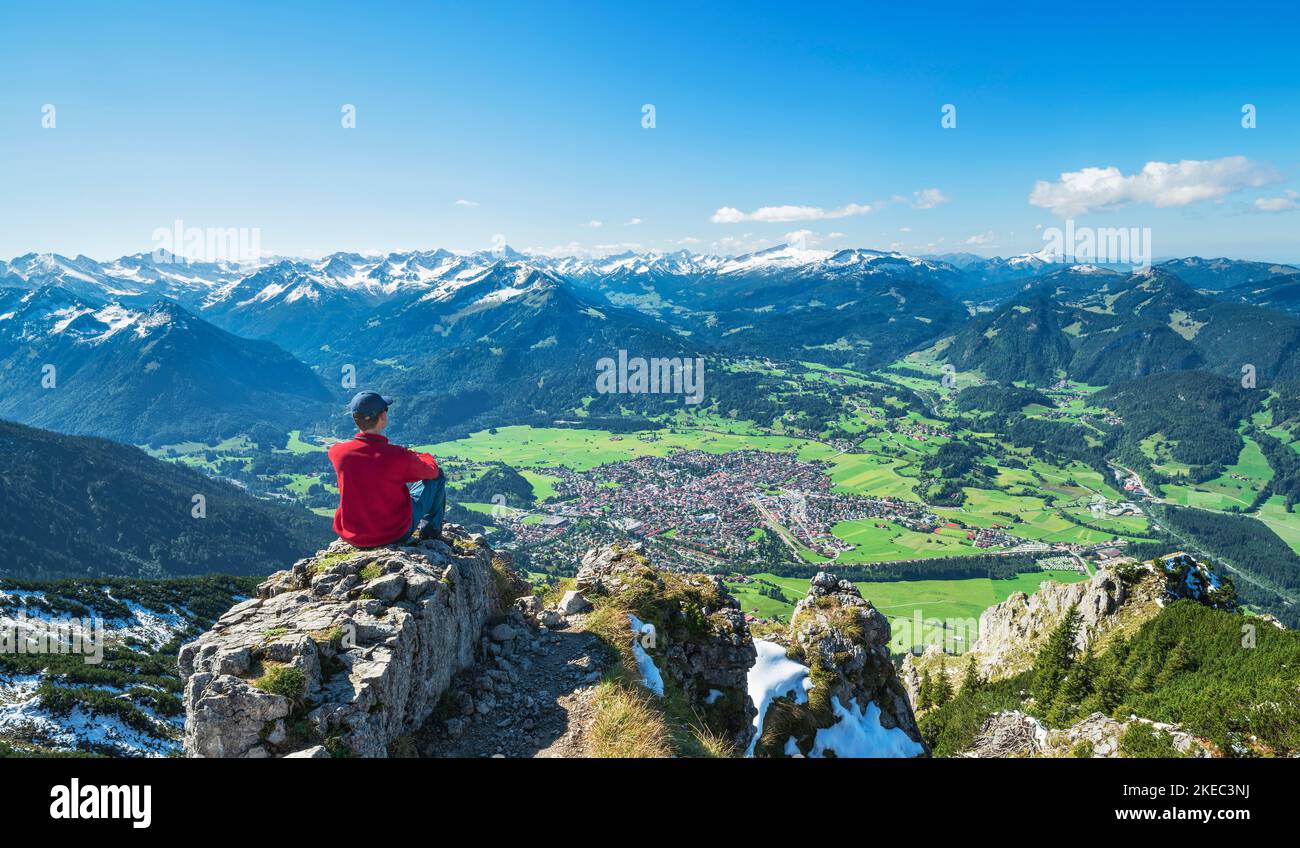Hiker at the top of Rubihorn enjoys view of Oberstdorf and snow covered ...