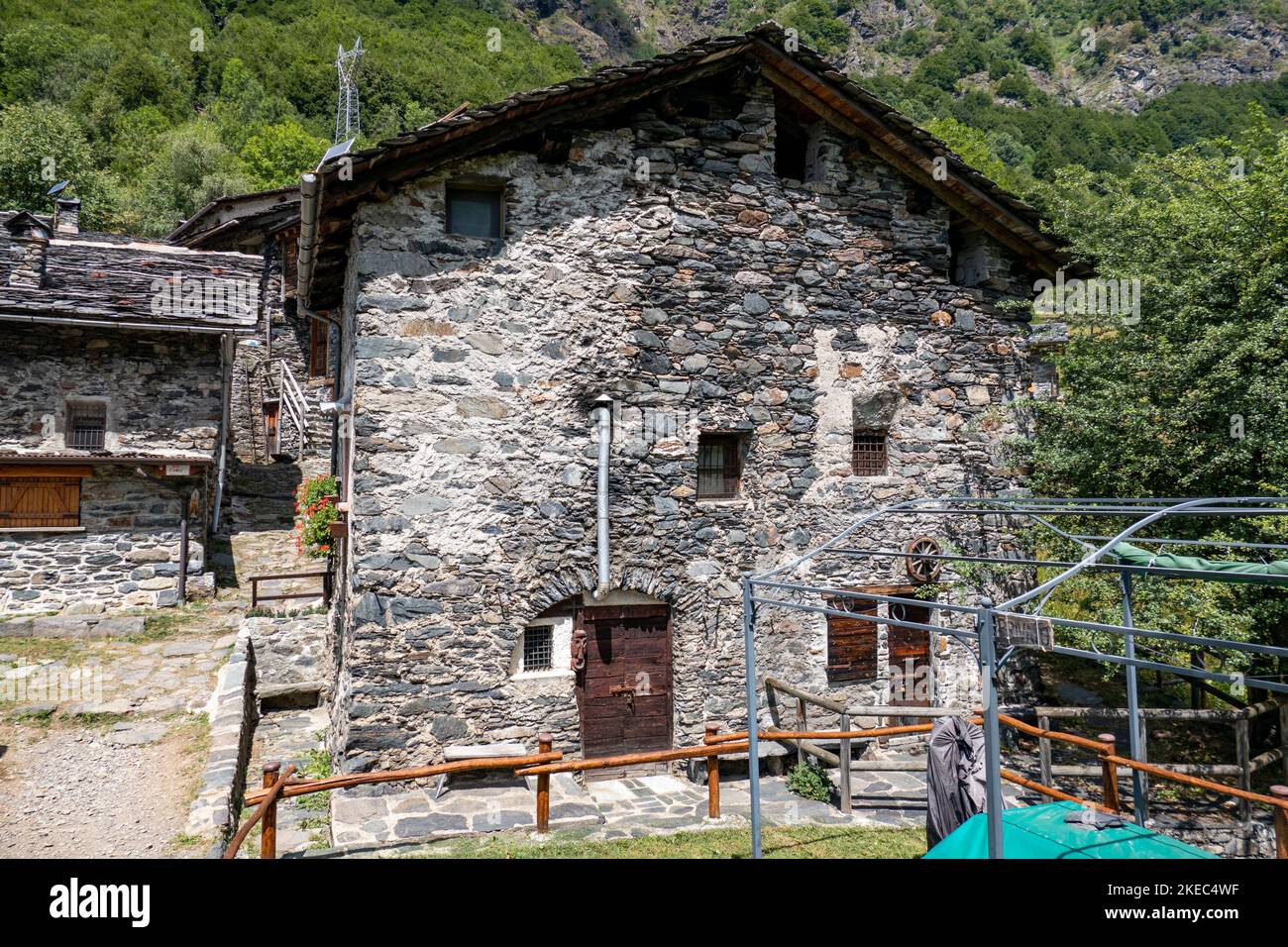 The exterior of an old stone house in a rural village with greenery ...