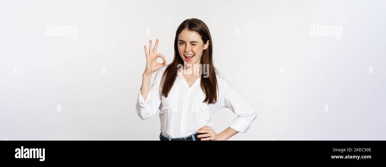 Smiling confident business woman, winking, showing okay ok sign ...