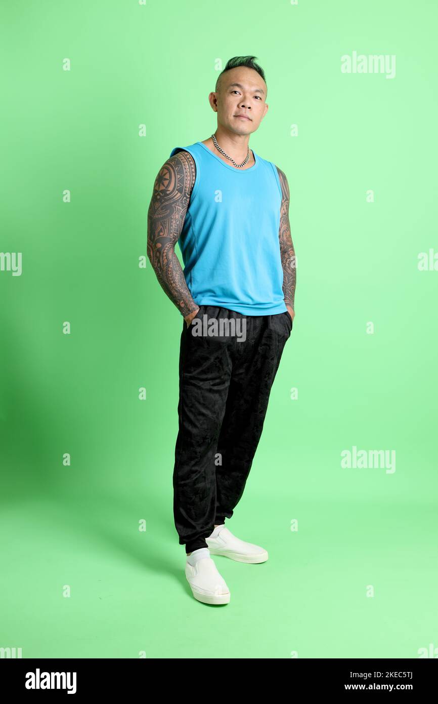 The 40s adult Asian man with tattoo standing on the green background ...