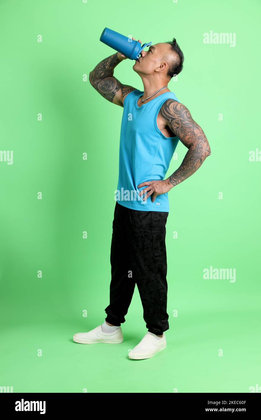 The 40s adult Asian man with tattoo standing on the green background ...