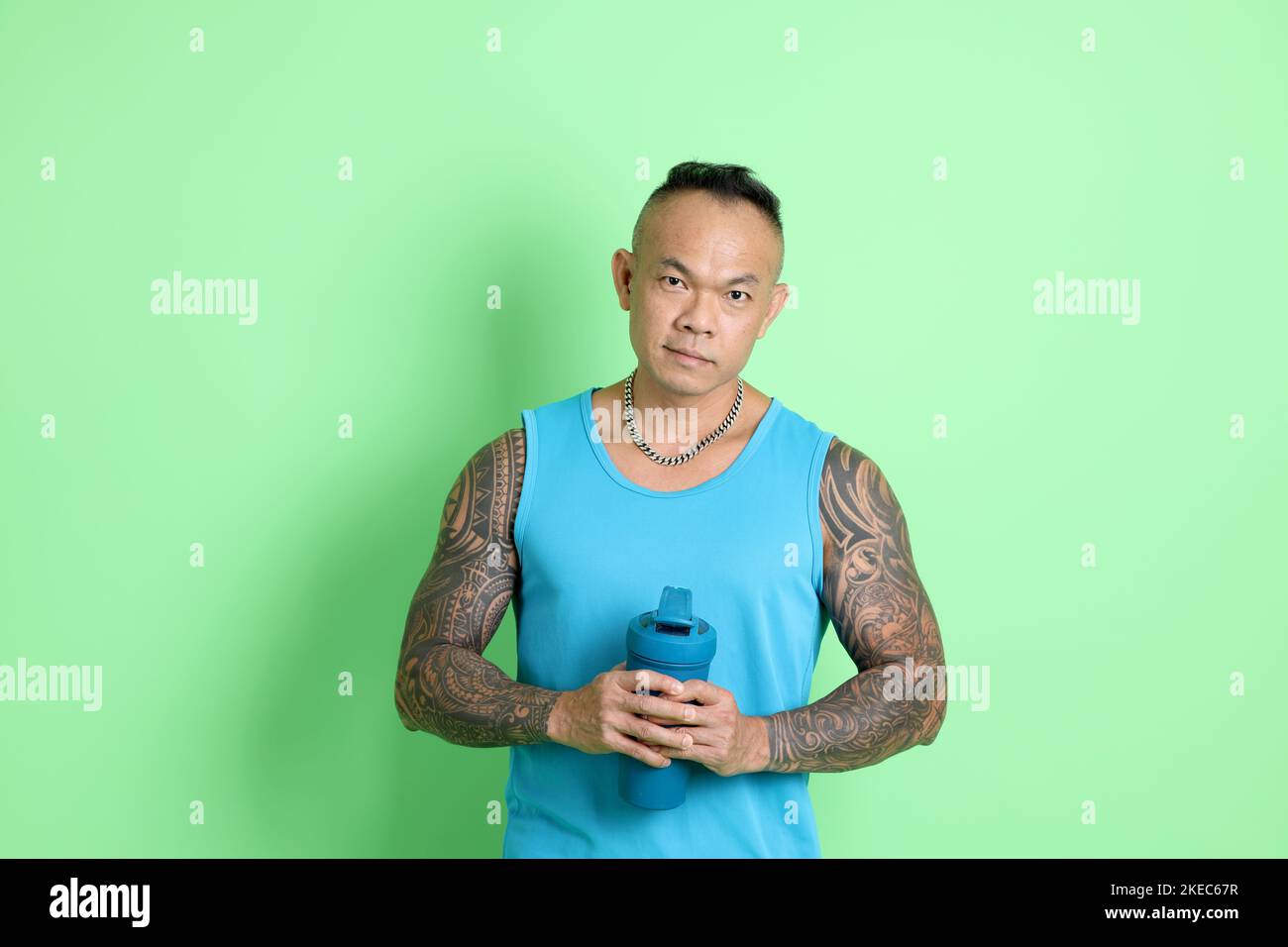 The 40s adult Asian man with tattoo standing on the green background ...