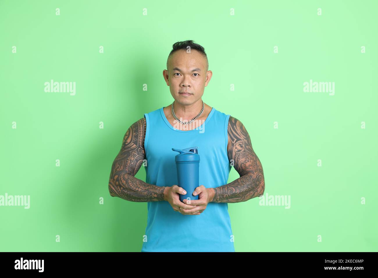 The 40s adult Asian man with tattoo standing on the green background ...
