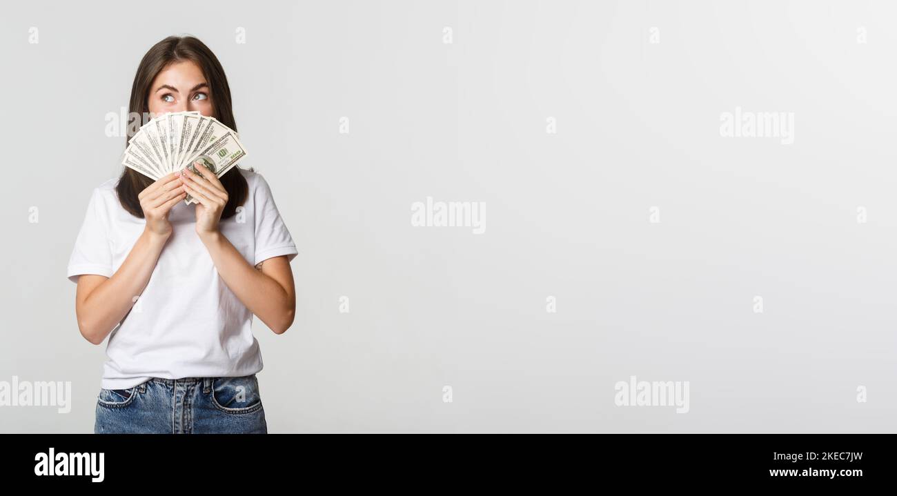 Excited dreamy girl holding money and looking upper left corner ...