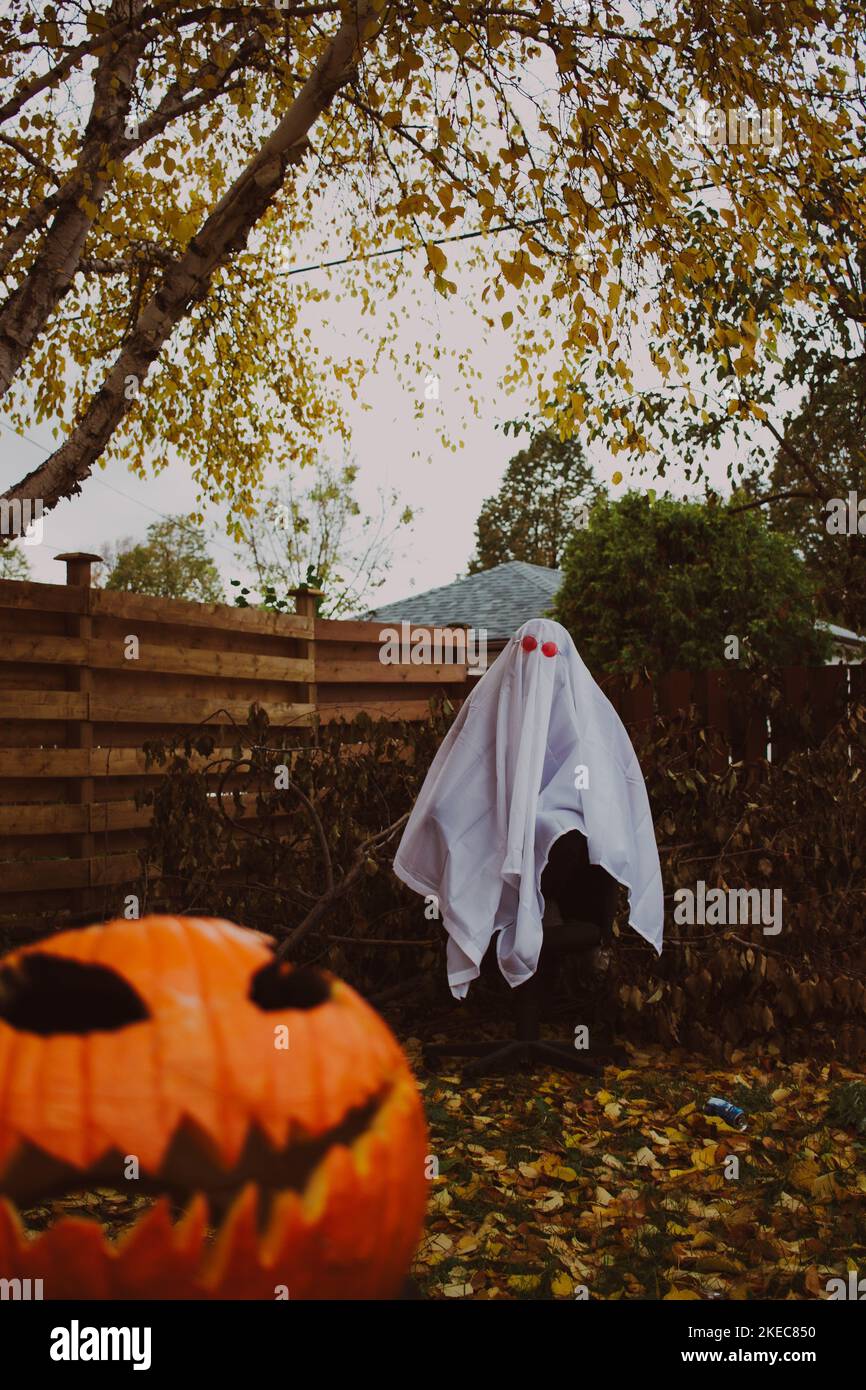 A curved pumpkin with a man wearing white ghost costume in the ...