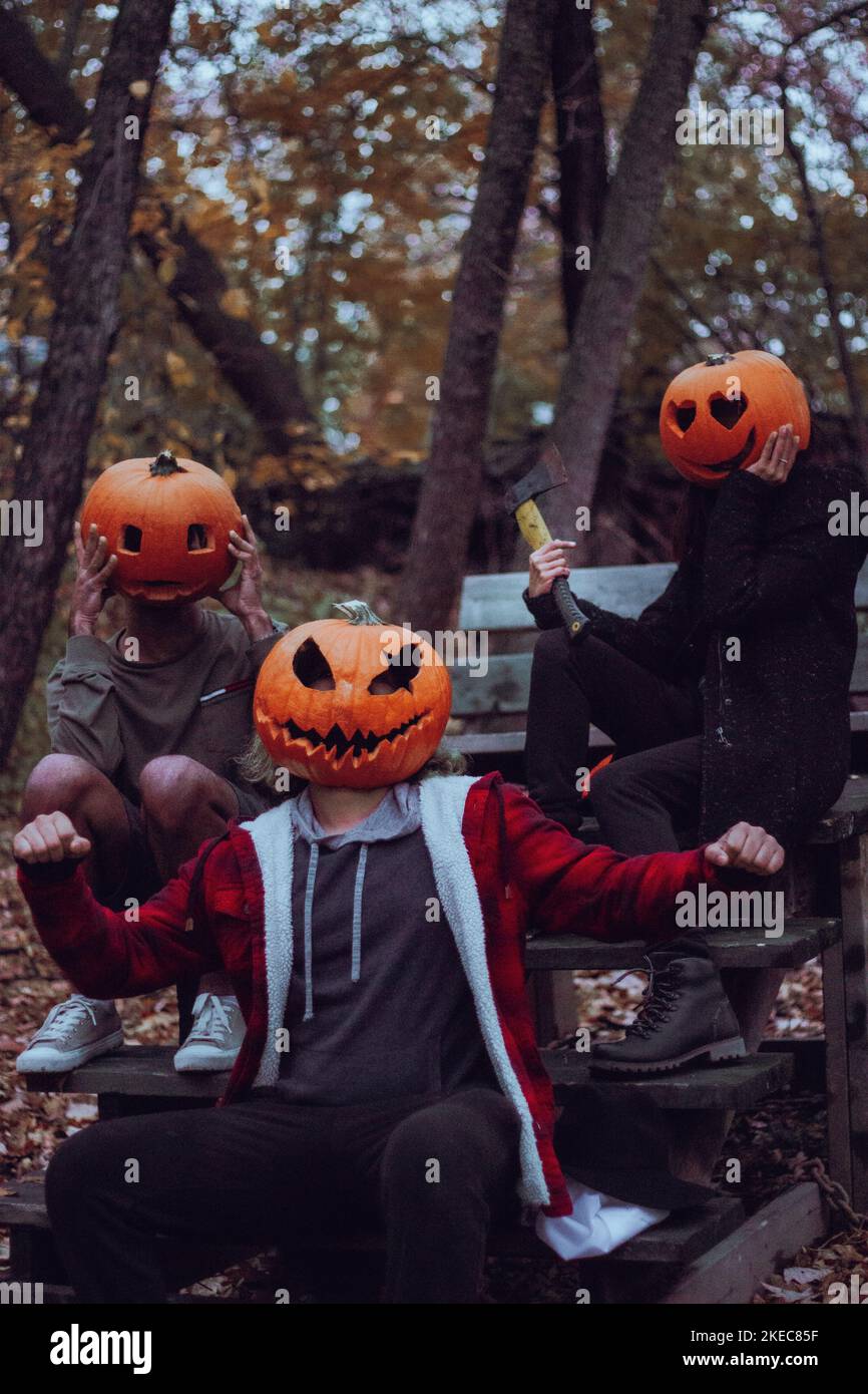 A vertical shot of men sitting on the bench and wearing curved pumpkins ...
