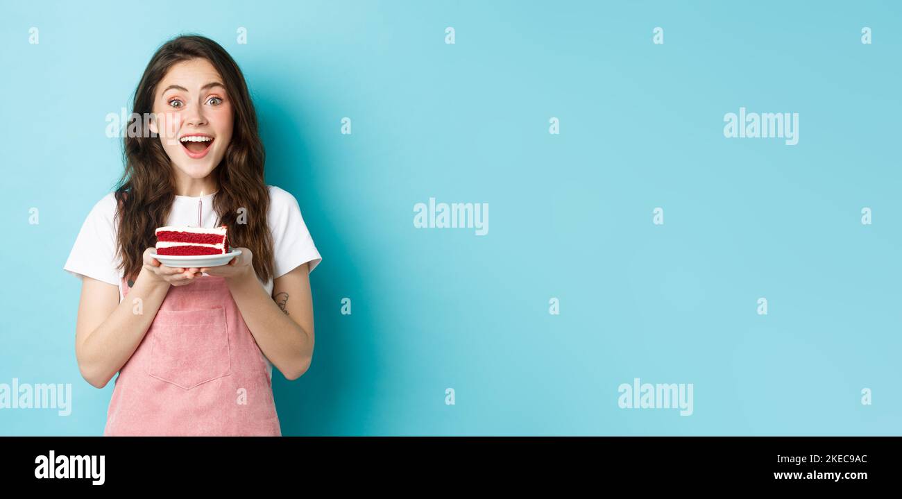 Holidays and party concept. Excited cute girl blowing candle on ...