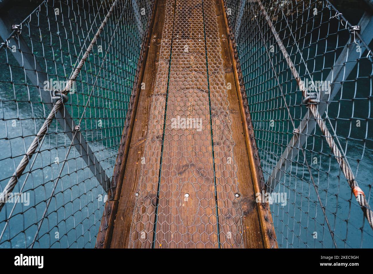 A wooden ground of a moving rope bridge over the river with metallic ...