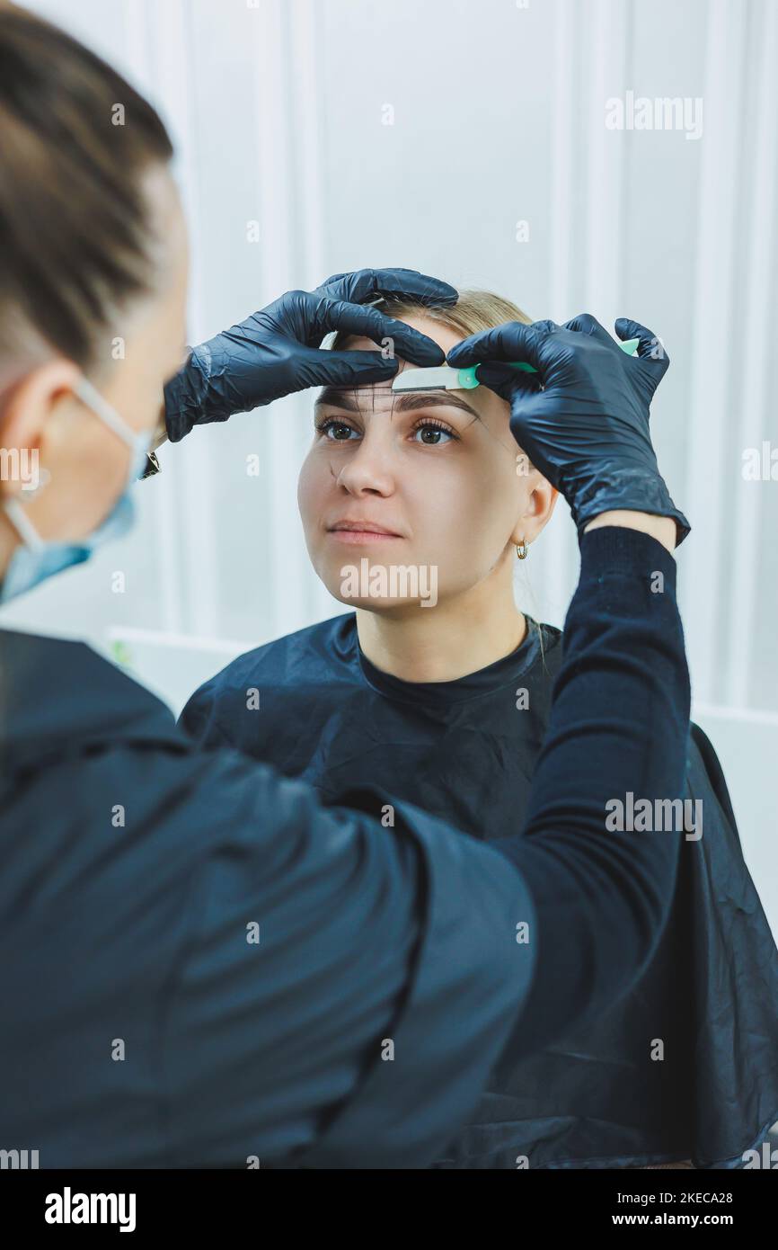 permanent eyebrows tattoo. permanent tattoo master checks the distance ...