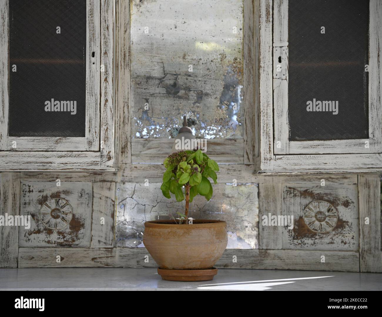 Antique wooden faded patina buffet with an aged mirror and a clay pot ...