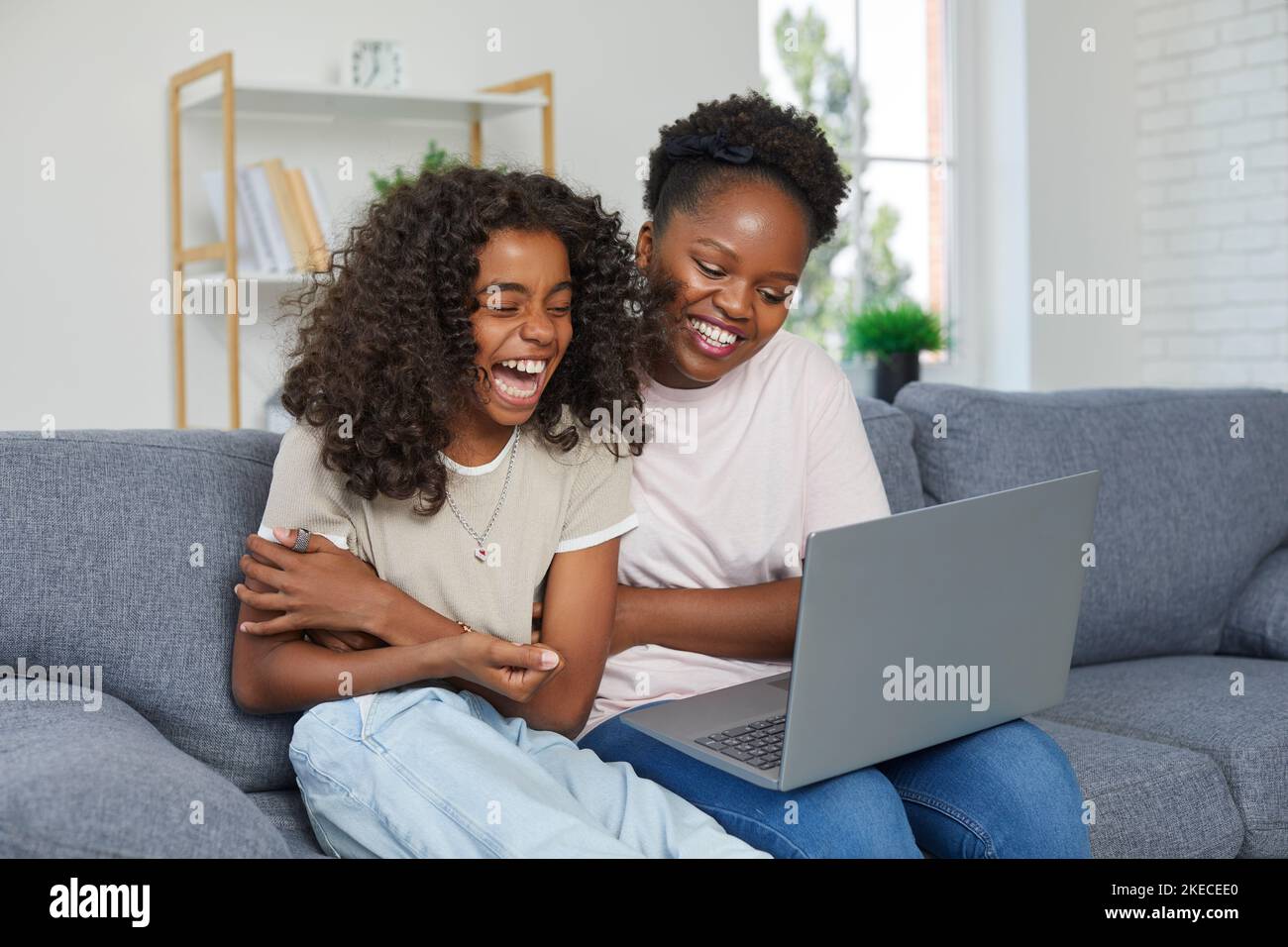 Happy family sitting on sofa at home, watching something funny on ...