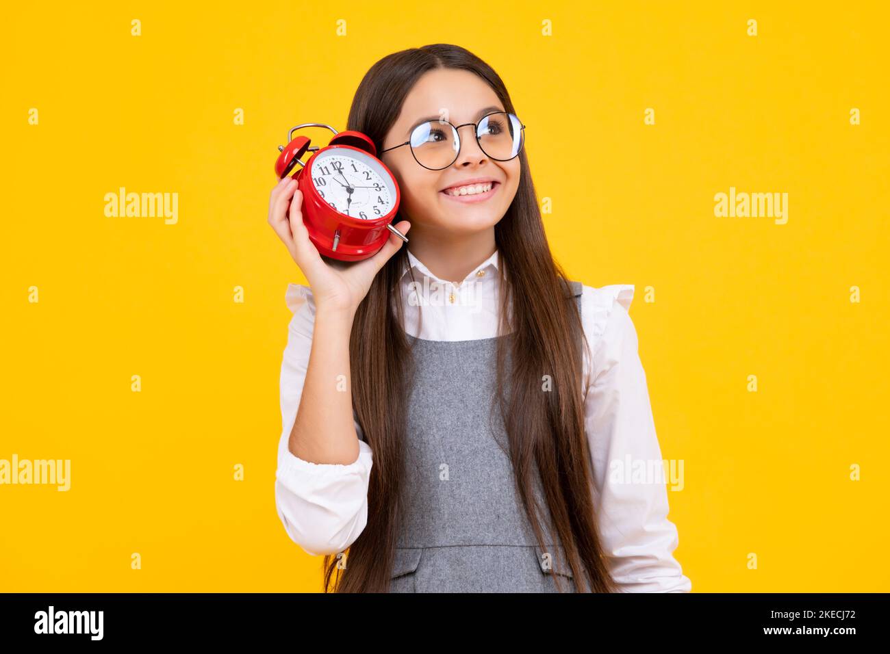 Teenager child hold clock isolated on yellow studio background ...