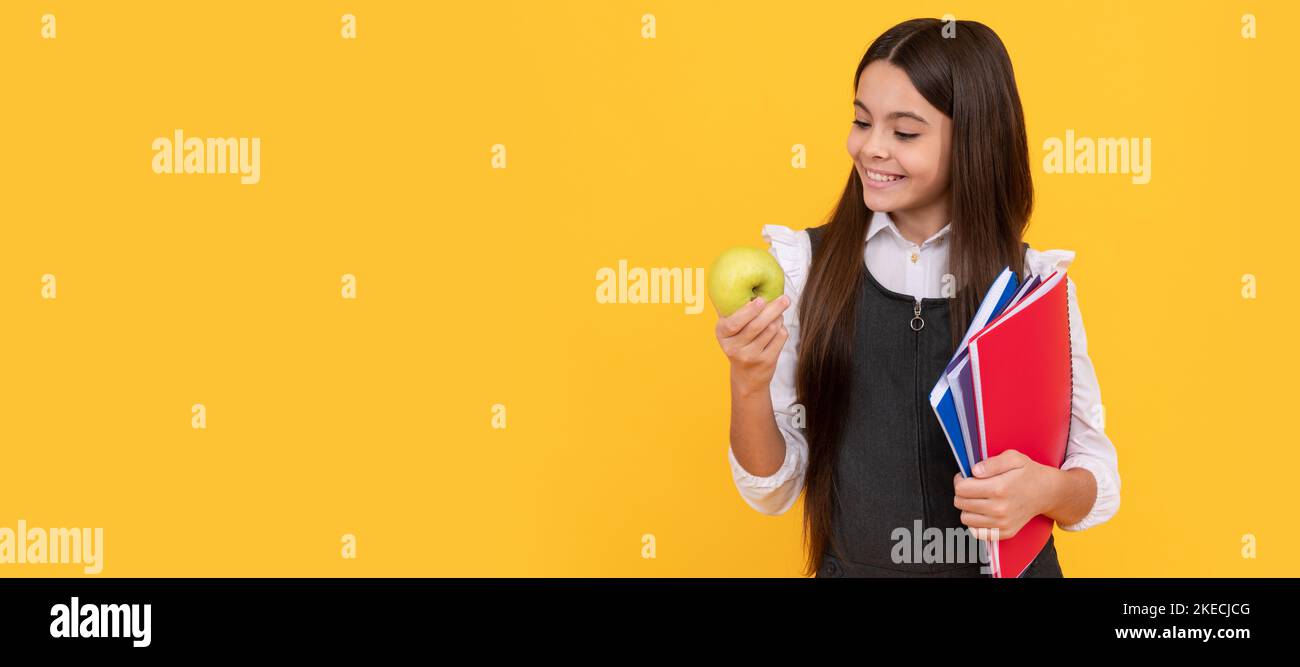Snack time. Happy girl look at apple holding schoolbooks. School snack ...