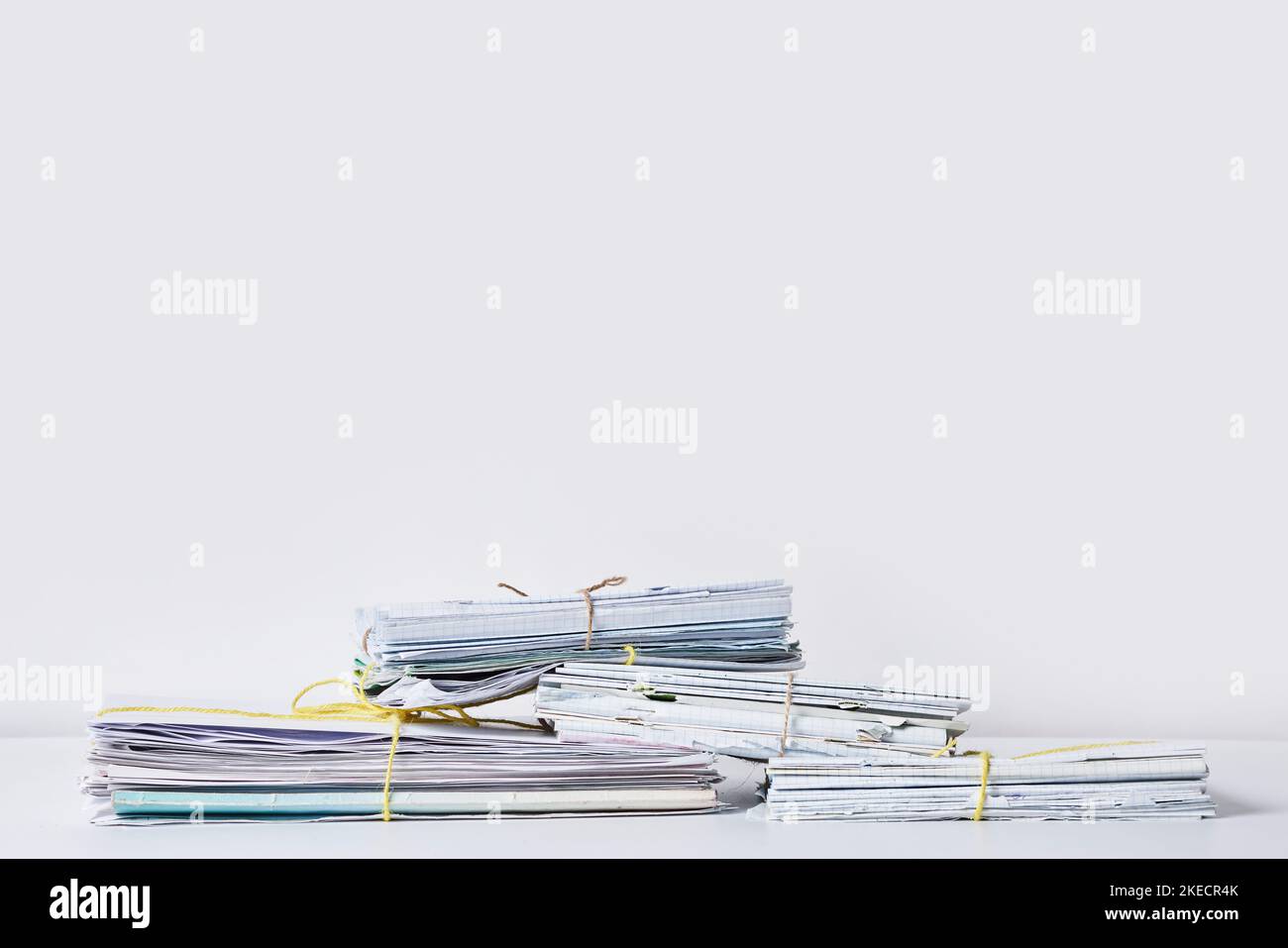 several stacks of paper on a white surface with yellow string tied to ...