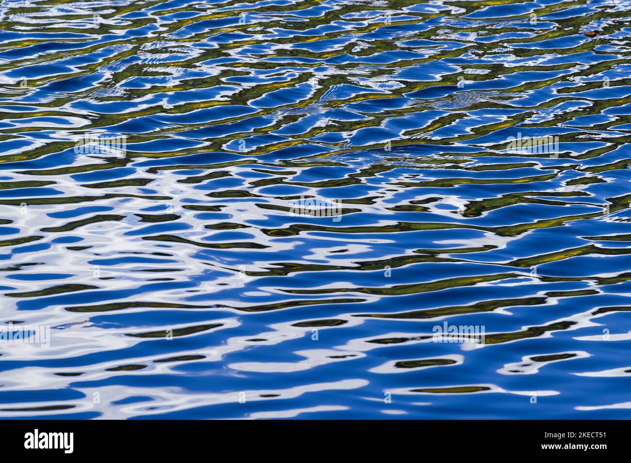 small waves and light reflections on the water surface of a lake ...