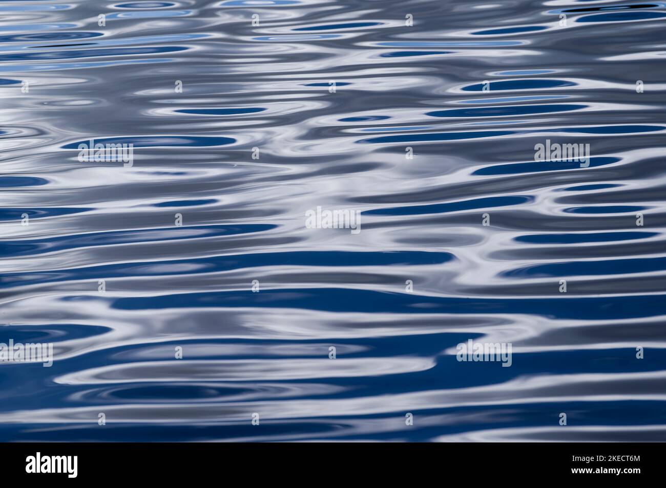 small waves and light reflections on the water surface of a lake ...