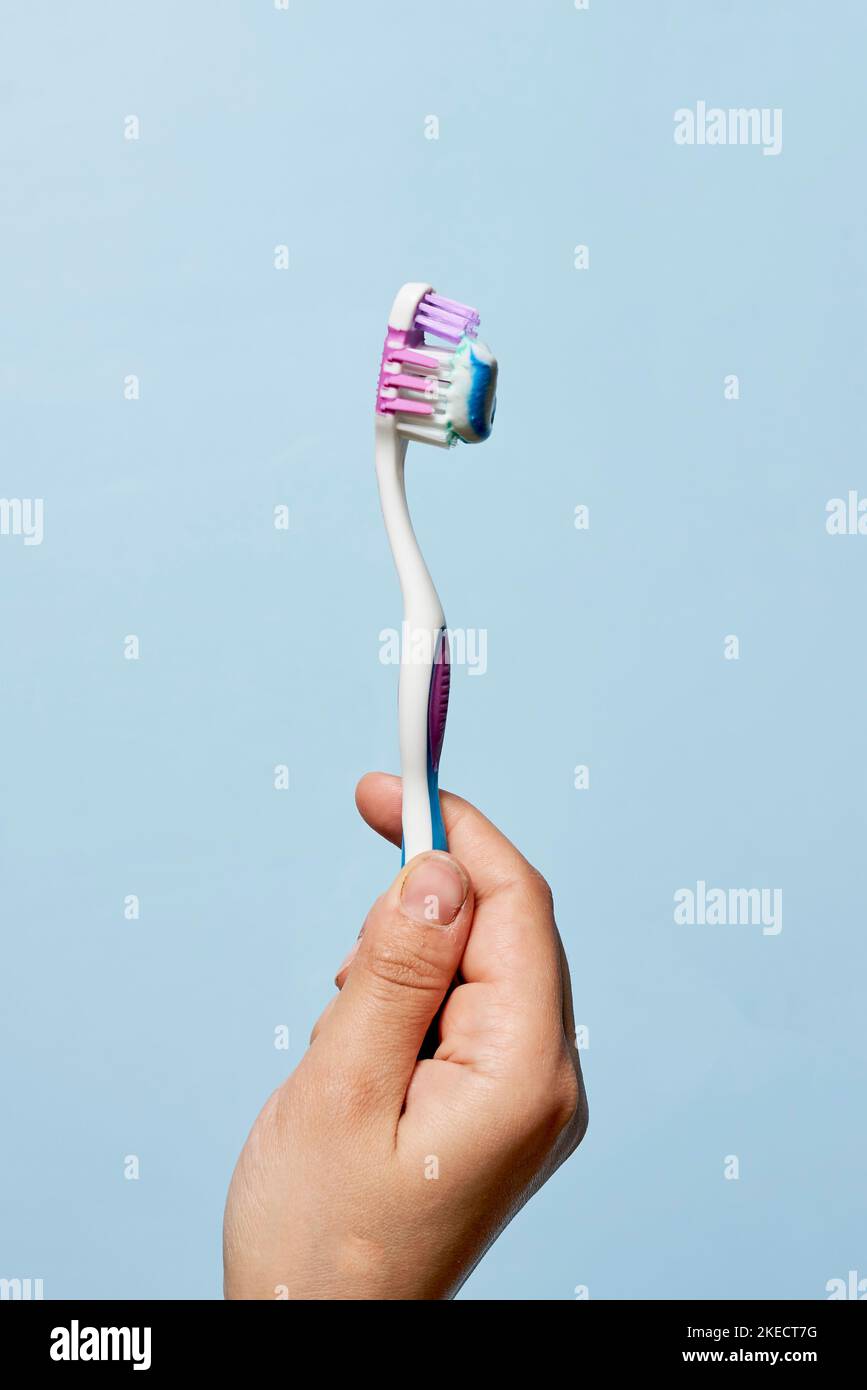 someone's hand holding a toothbrush in front of a blue sky and white ...