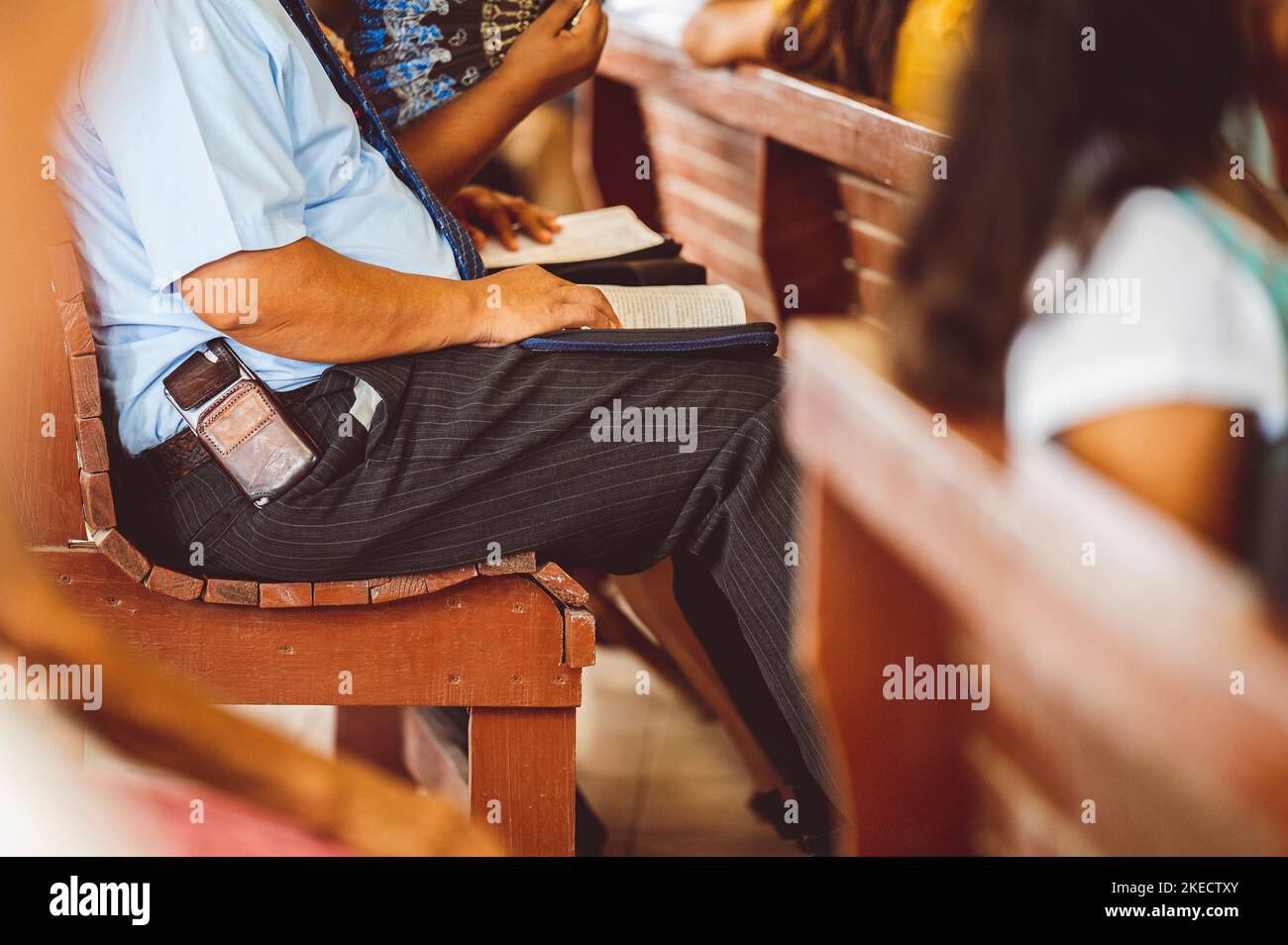 a Selective focus closeup of people sitting in a church on benches and ...