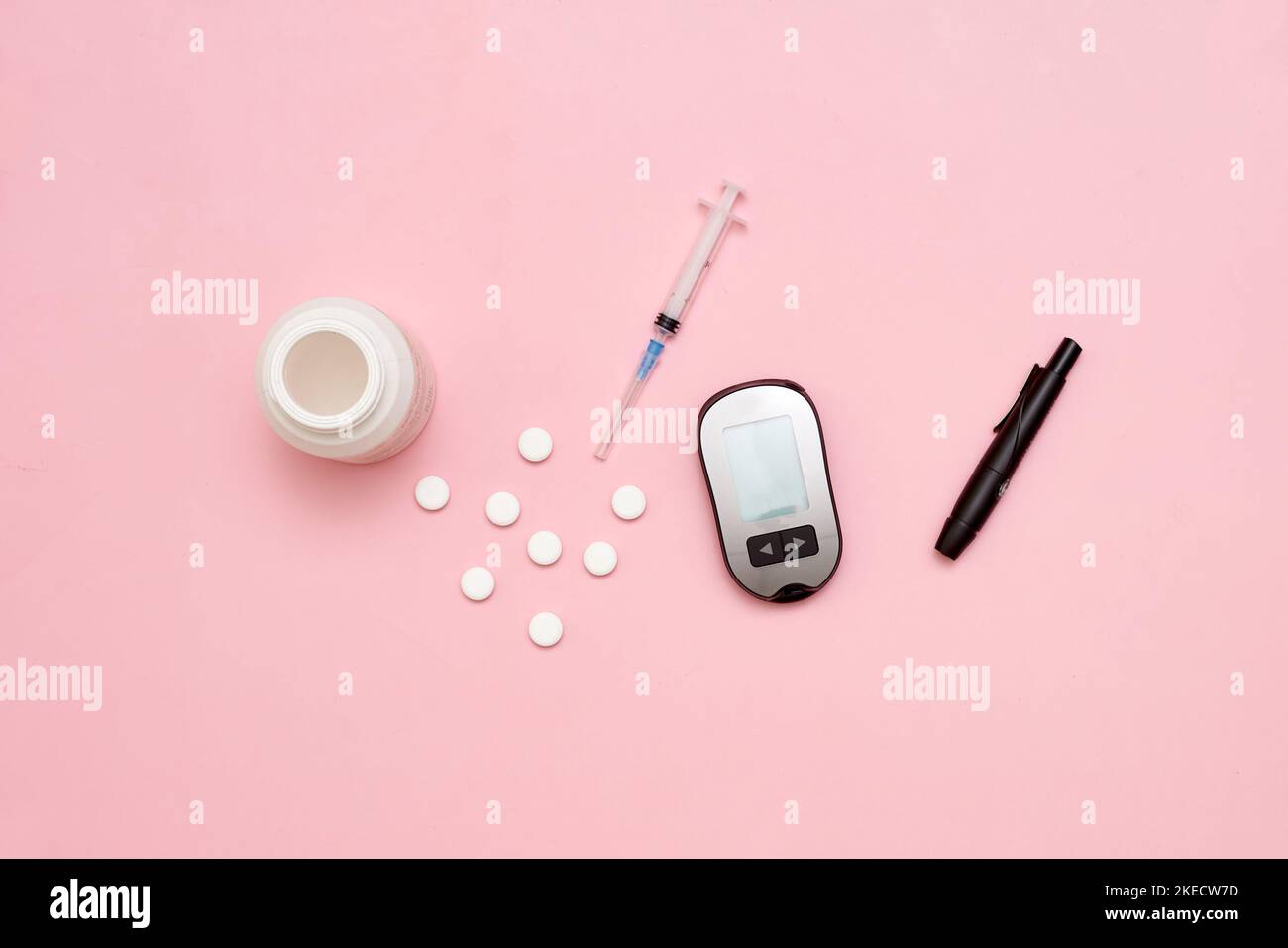 an electronic device, pills, and a pill bottle on a pink background ...