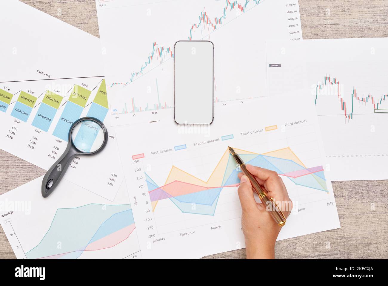 a person's hand holding a pair of scissors next to several papers with ...