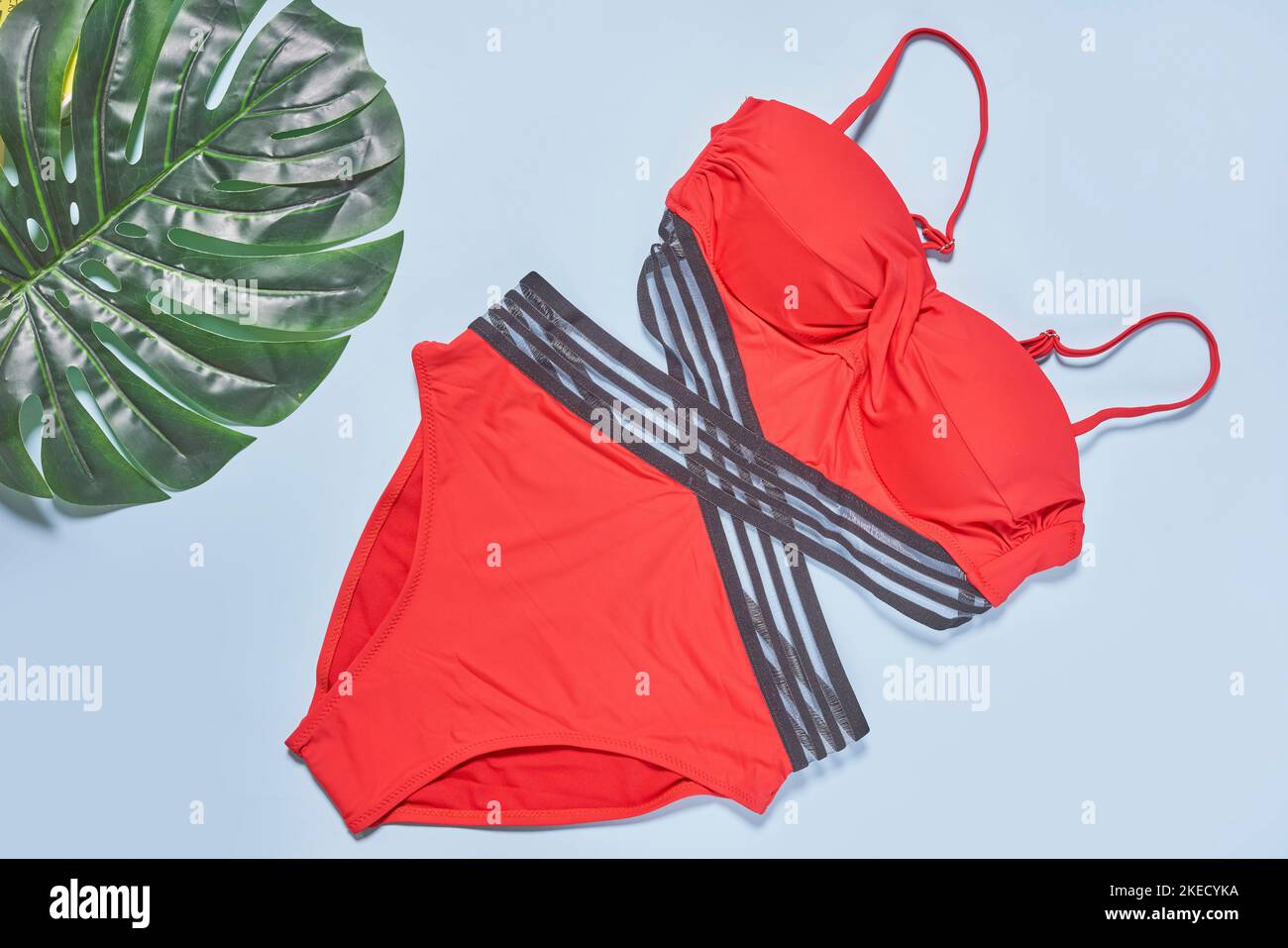 two red swimsuits with grey and white stripes on the bottom, next to a ...