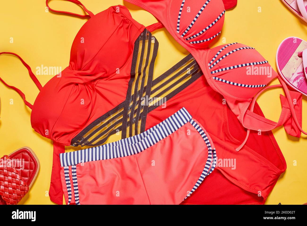 red swimsuits and flip flops laid out on a bright yellow surface with ...
