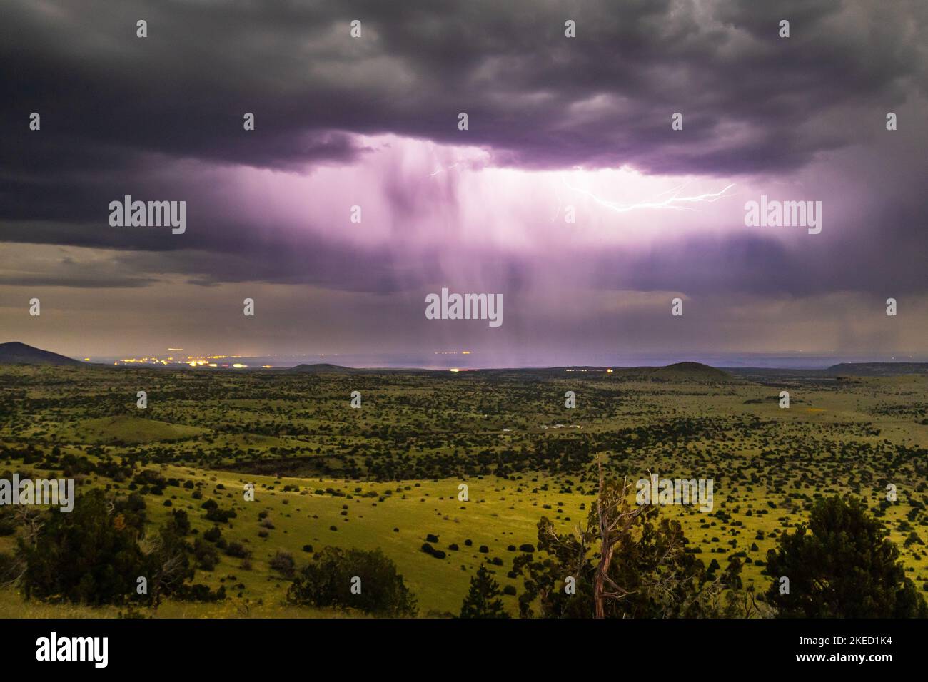 Lighting bolt under a cloud as rain comes down over open wilderness in ...