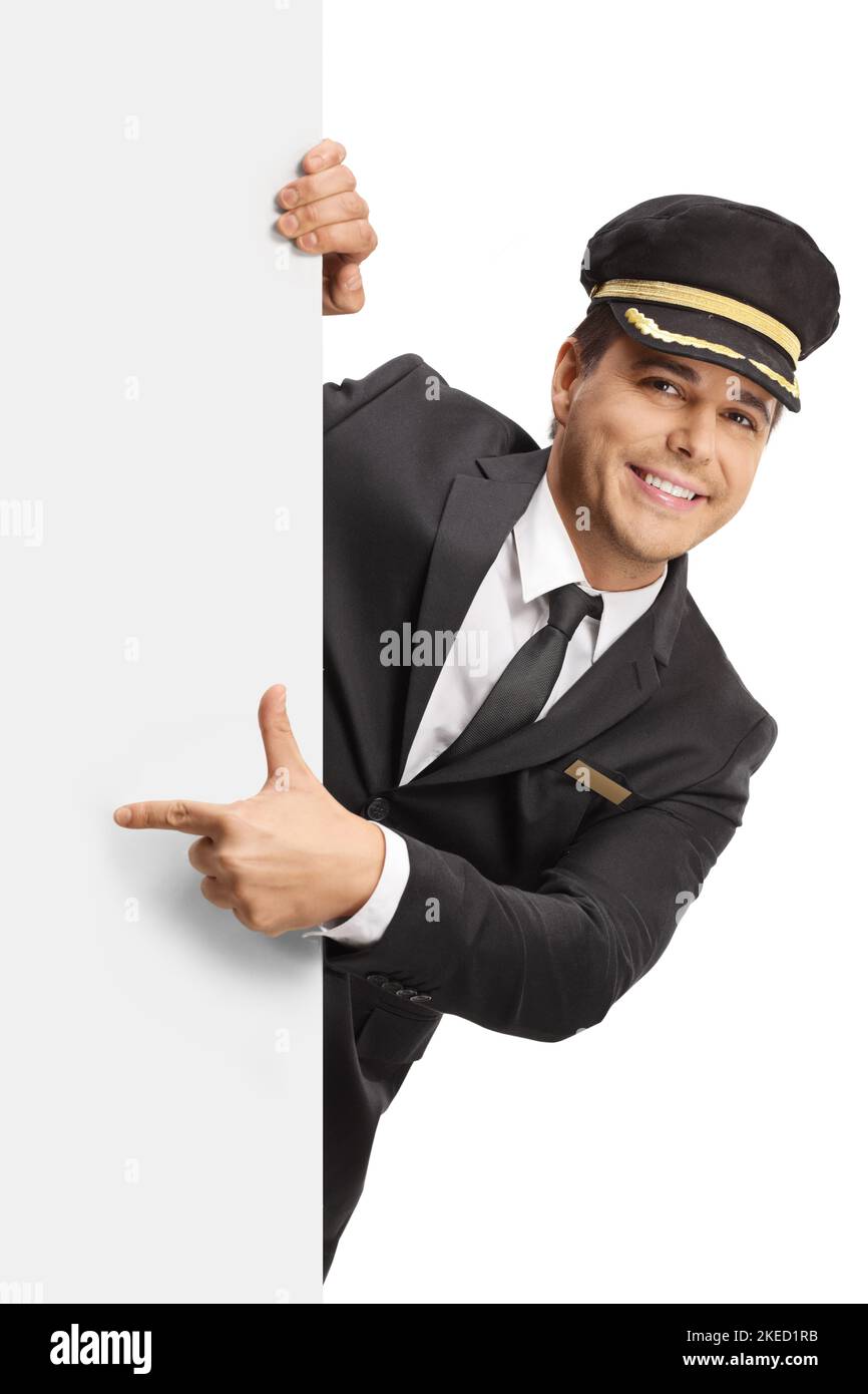 Smiling bellboy standing behind a white panel and pointing isolated on ...