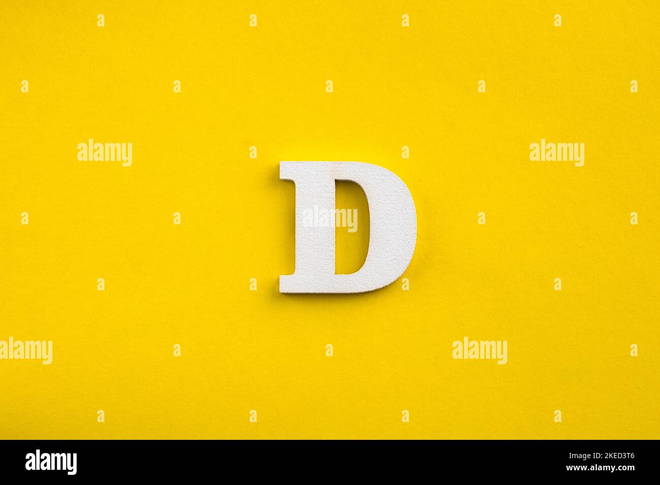 Alphabet letter D - White wood letter on yellow colored background ...
