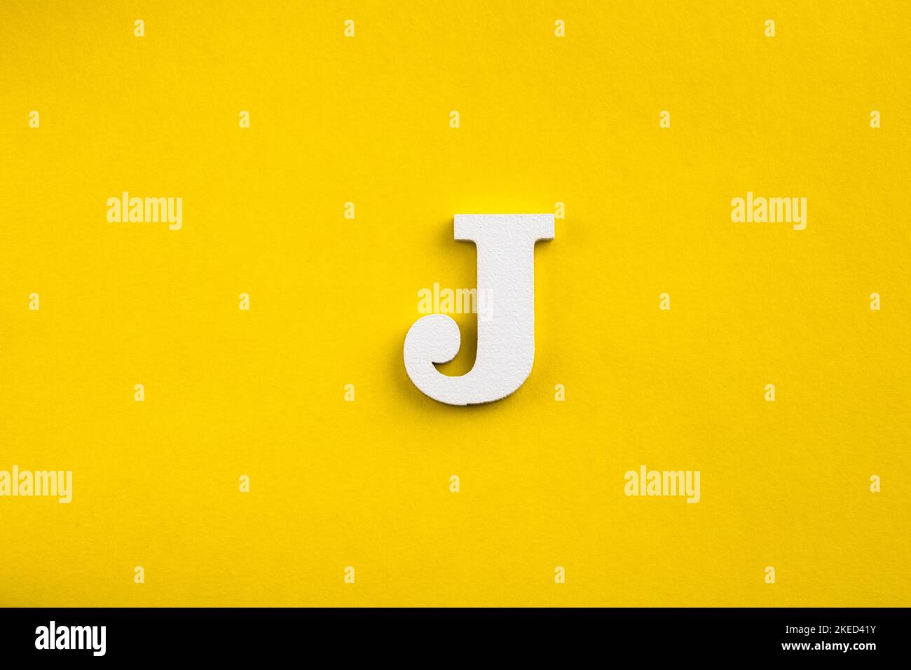 Alphabet letter J - White wood letter on yellow colored background ...