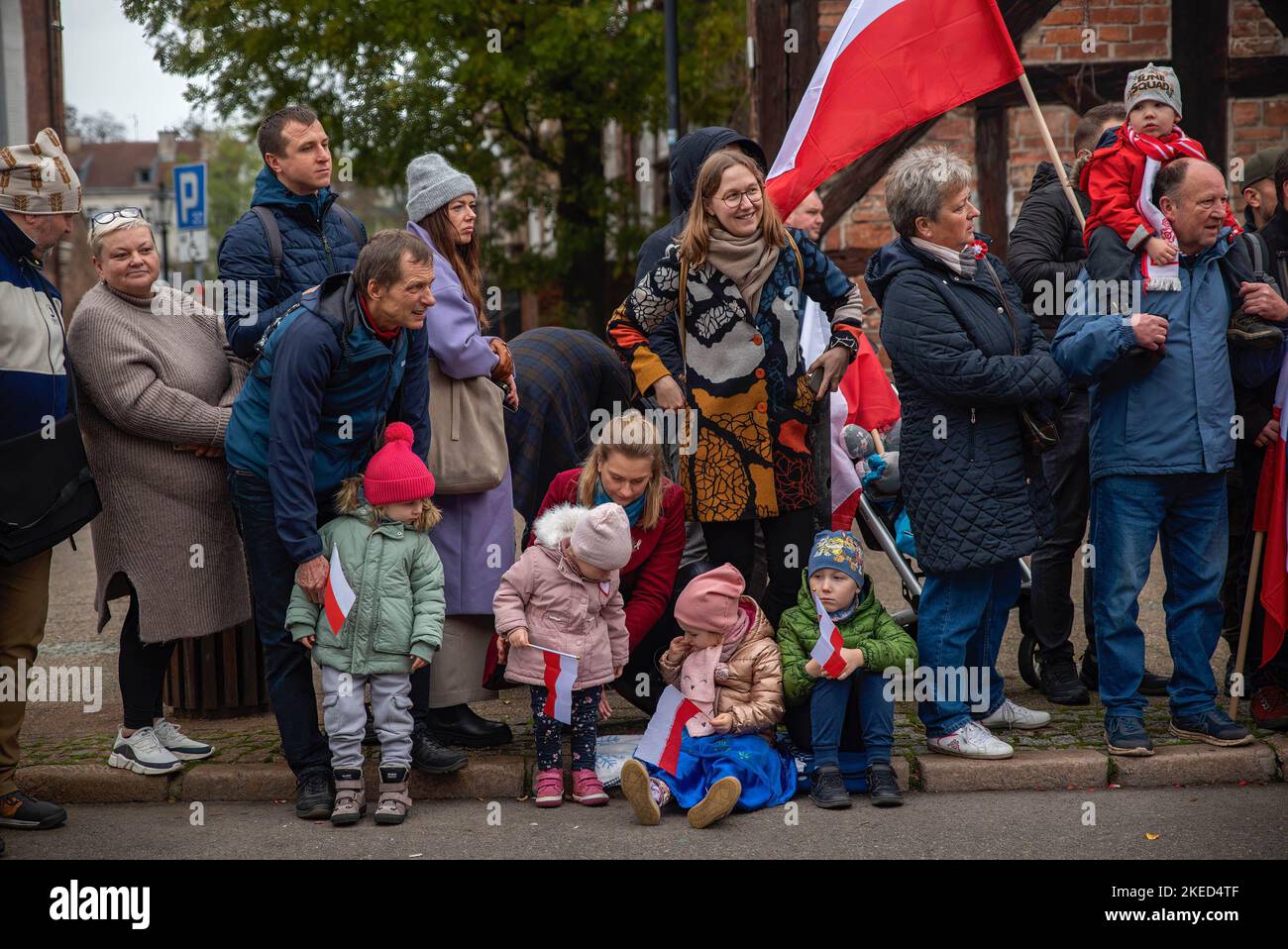 Residents with children stand on the pavements as they watch the parade ...