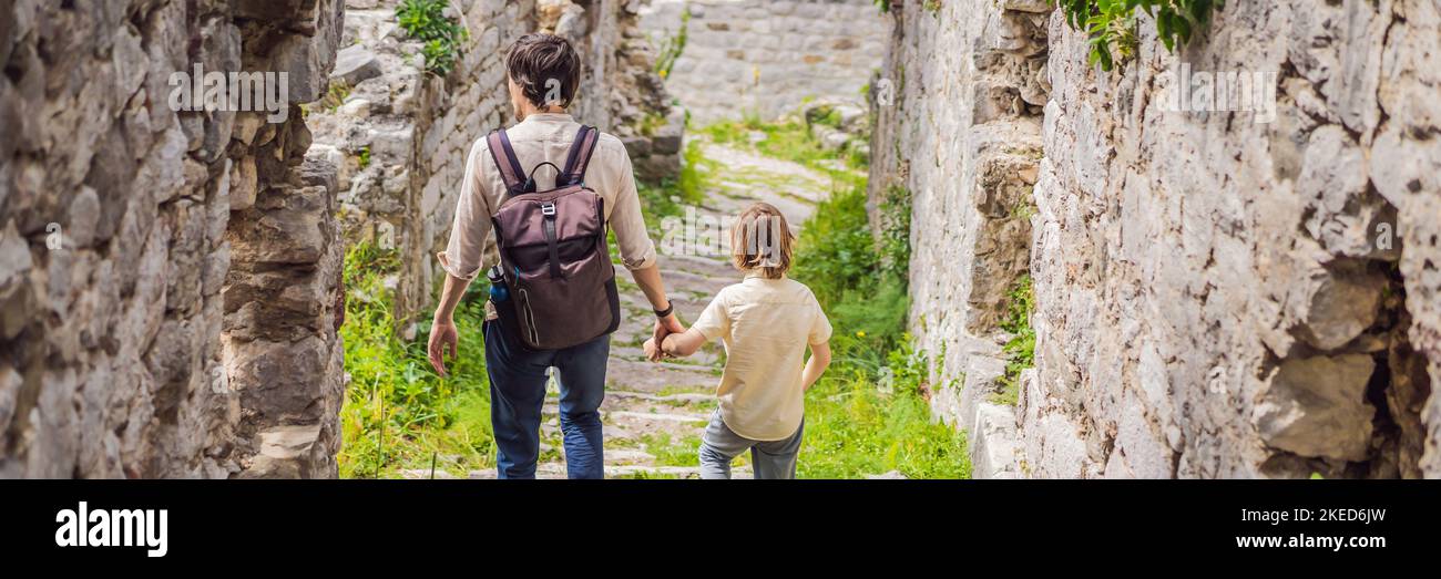 BANNER, LONG FORMAT Dad and son tourists walks through the old town of ...