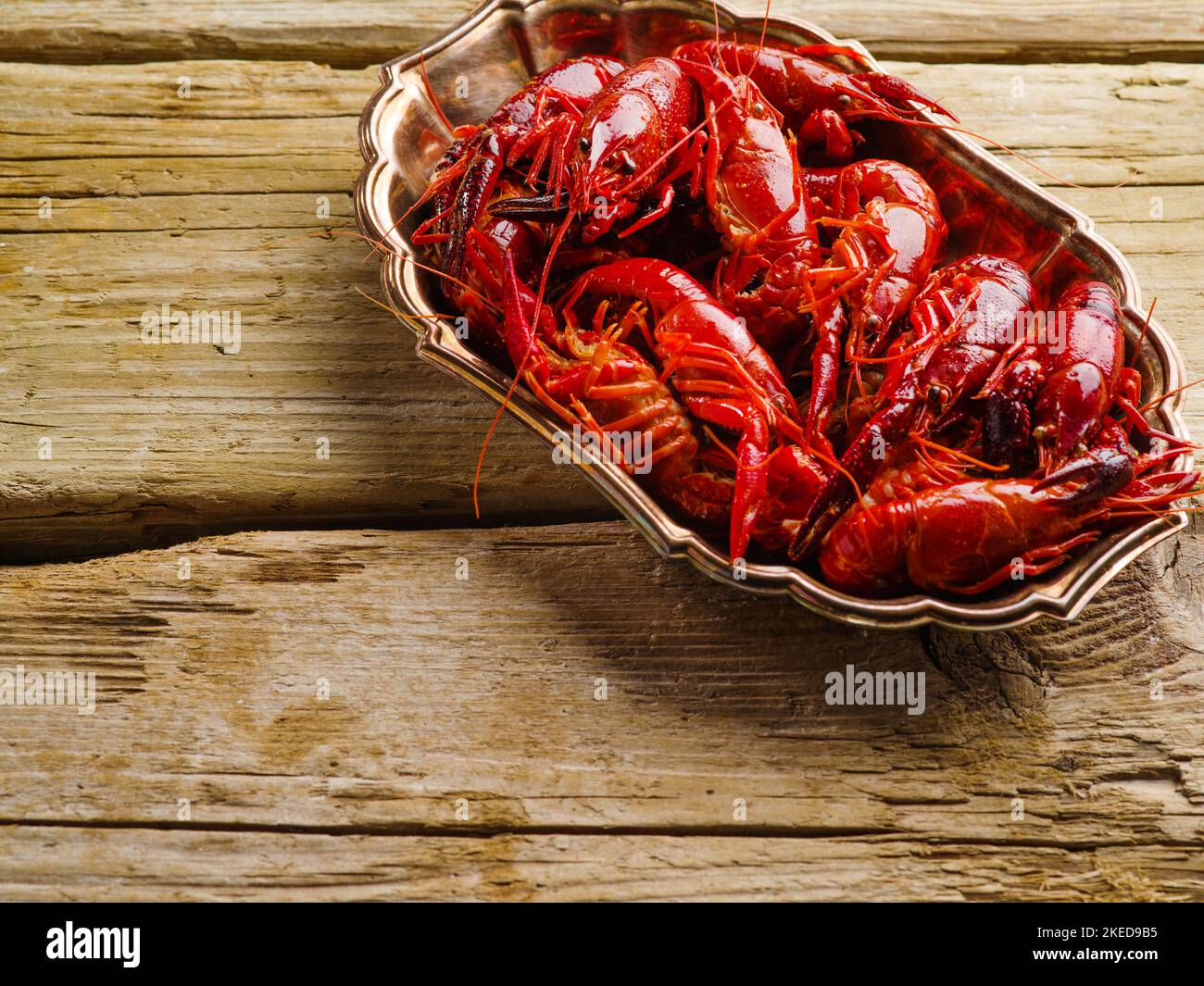 Dish with boiled crayfish on a wooden kitchen table. Minimalism ...
