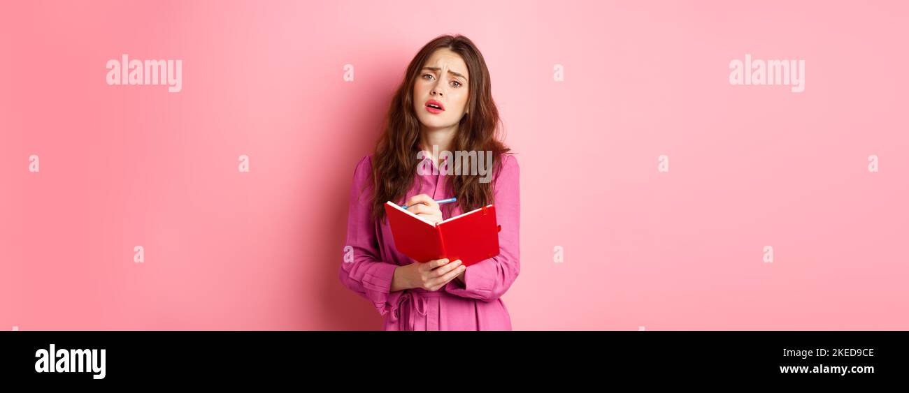 Coy romantic girl sighing, writing in her diary about sad moment ...