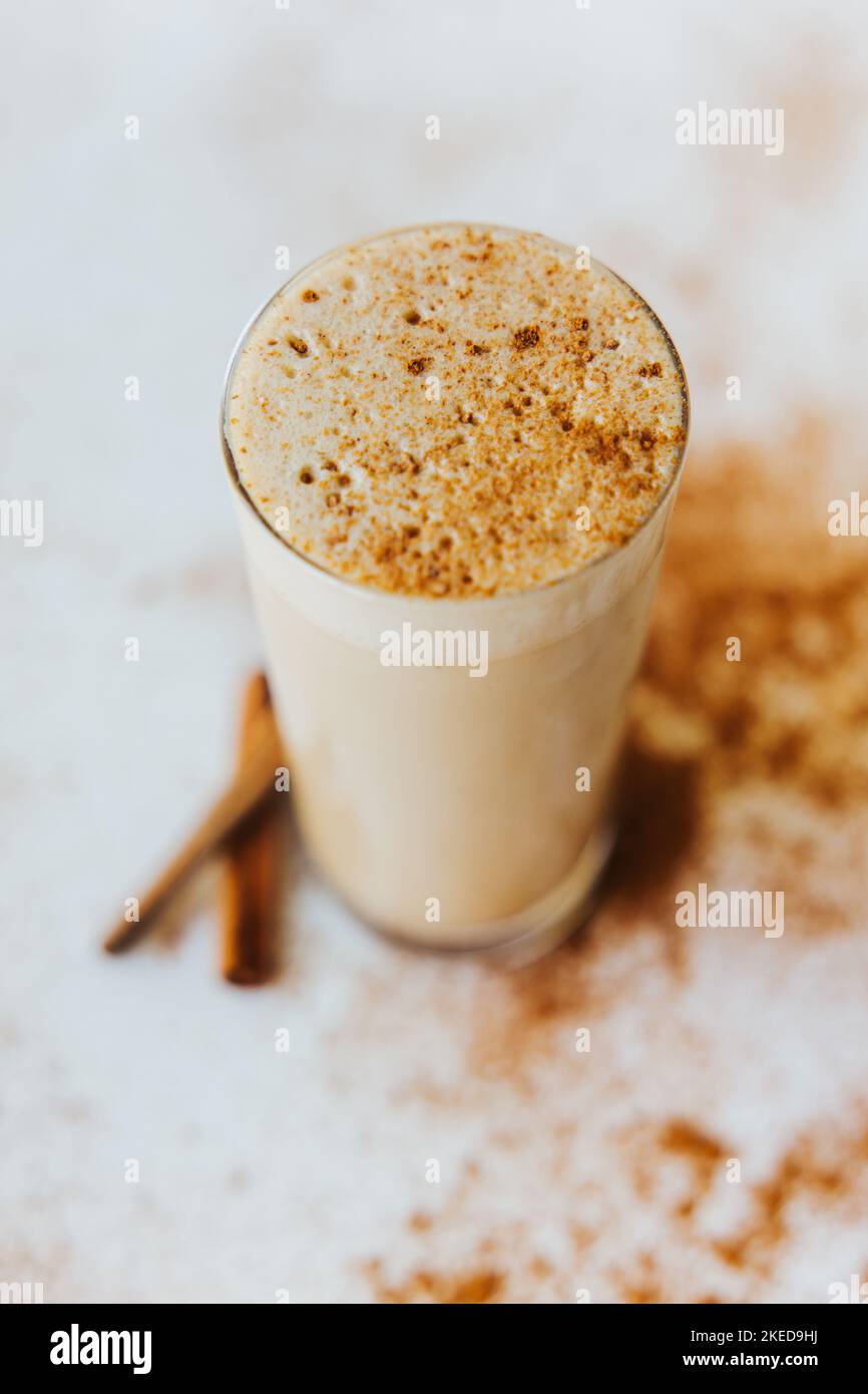 A top view of a glass of a beige cinnamon mocha shake, sprinkled with ...