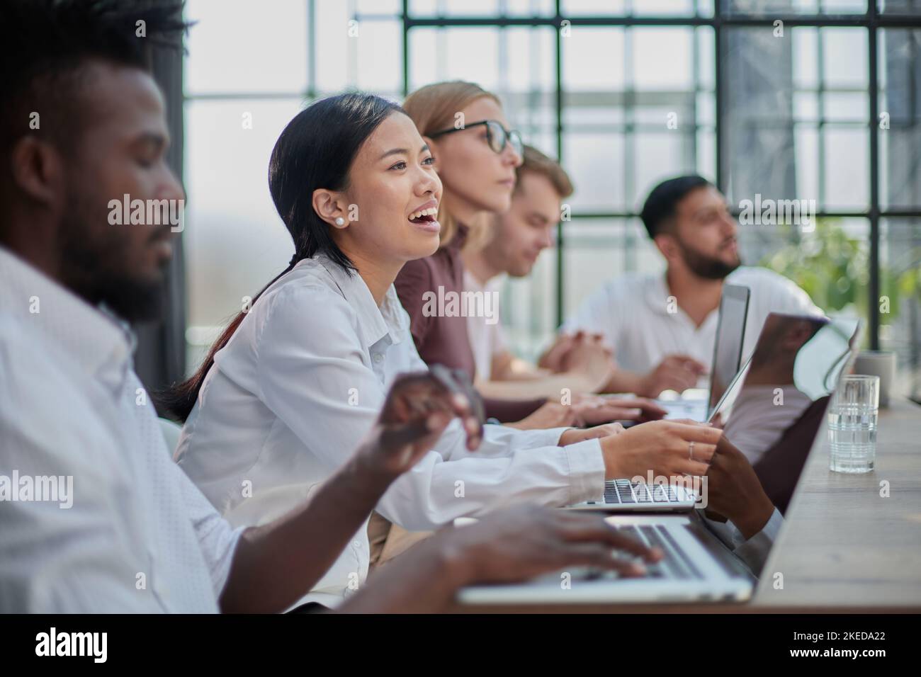 Multicultural colleagues sitting at desk near digital devices and ...