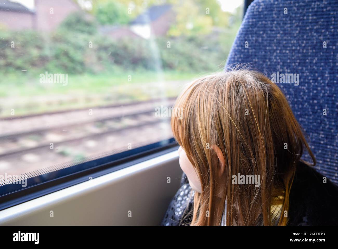 Girl travels by train looking out of the window during a rail journey ...