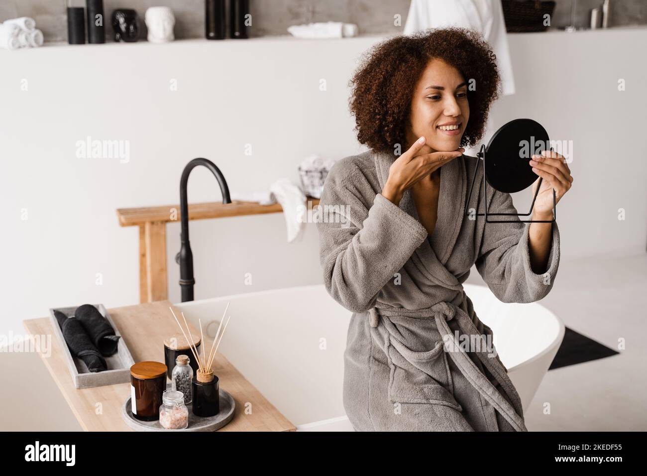 African girl is looking on acne pimples on her face in the mirror. Skin ...