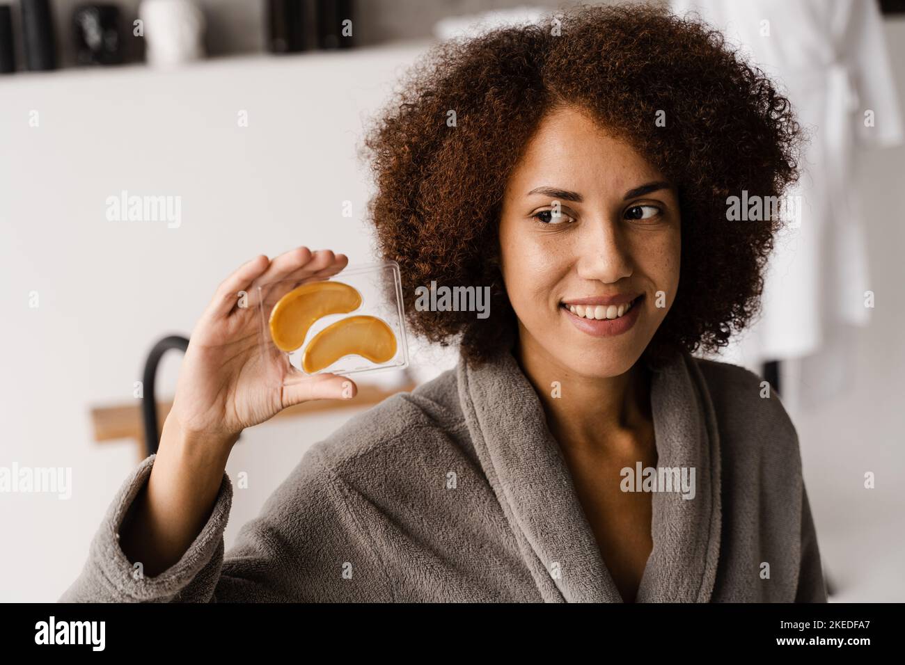 Smiling African girl with golden eye patches in her hands. Cosmetic ...