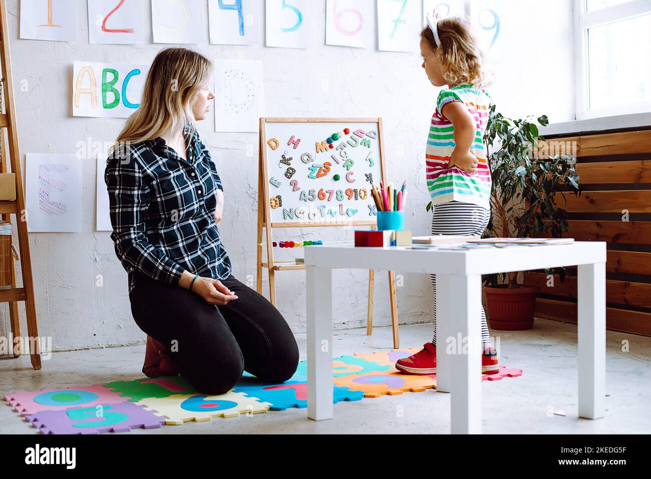 Female teacher explain exercises and check homework with girl near ...