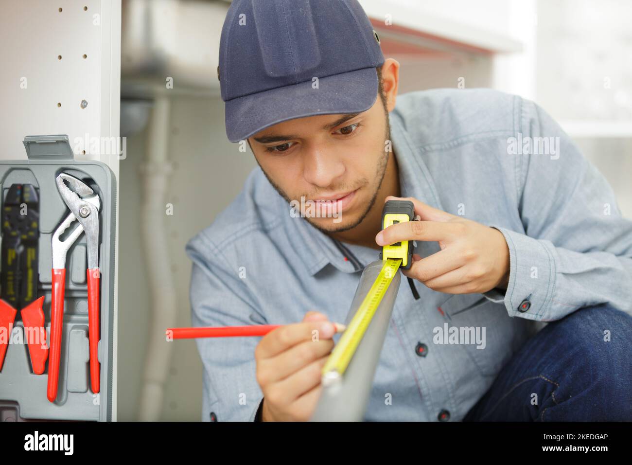 young tradesman measuring pvc pipe Stock Photo - Alamy