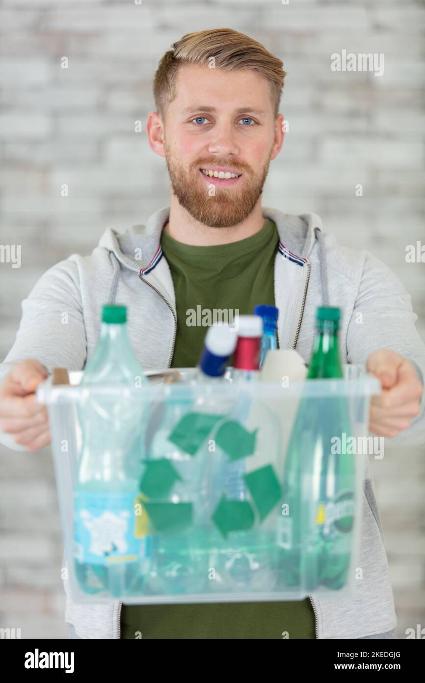 portrait of a smiling young man carrying recycle container Stock Photo ...