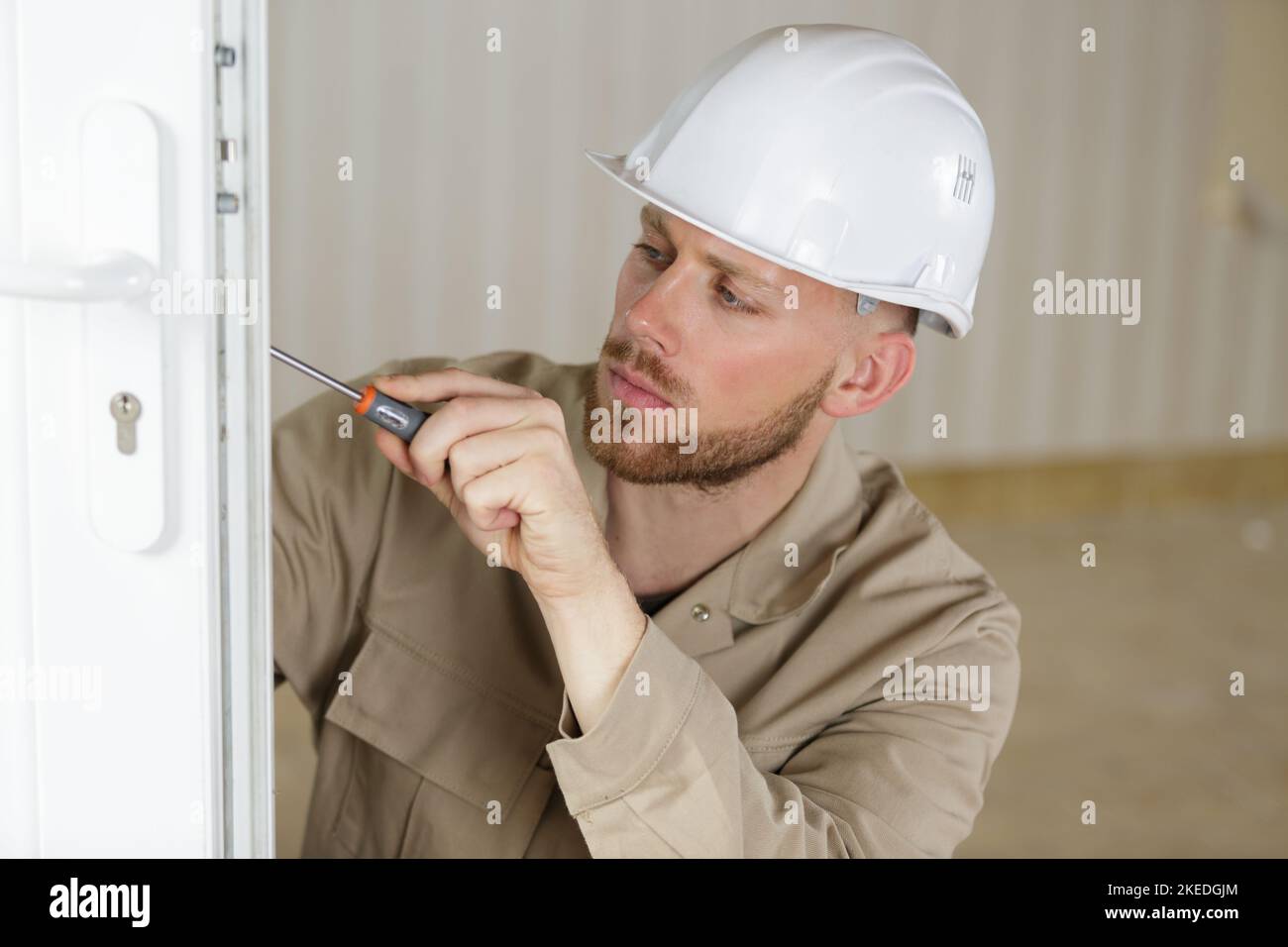 young male contractor using screwdriver on a door lock mechanism Stock ...