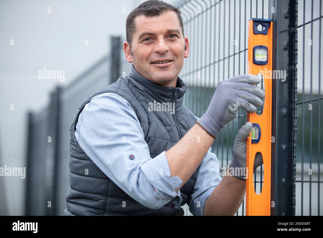happy man check the level of new fence gates Stock Photo - Alamy