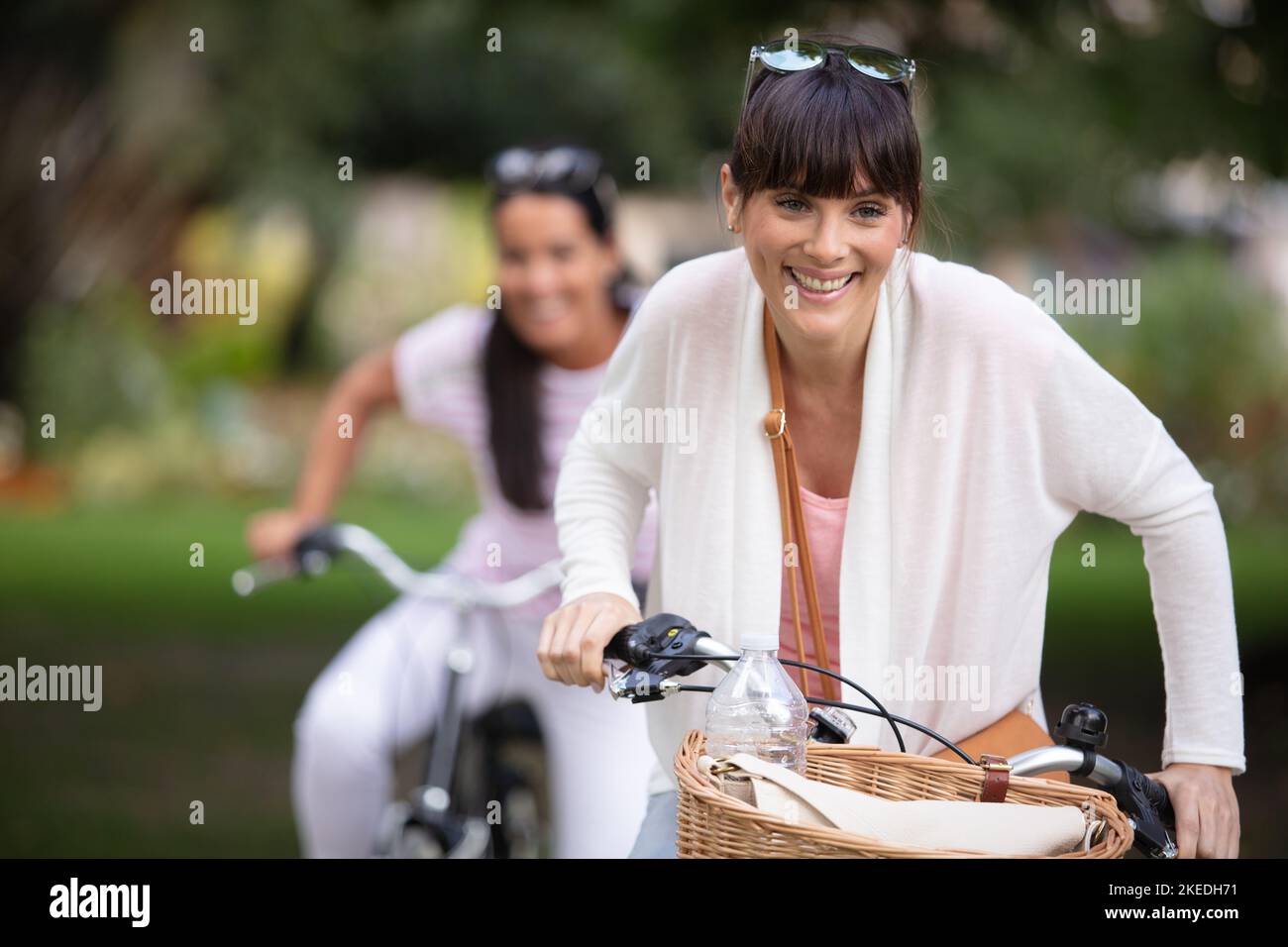 two girlfriends on bikes talking and laughing Stock Photo - Alamy