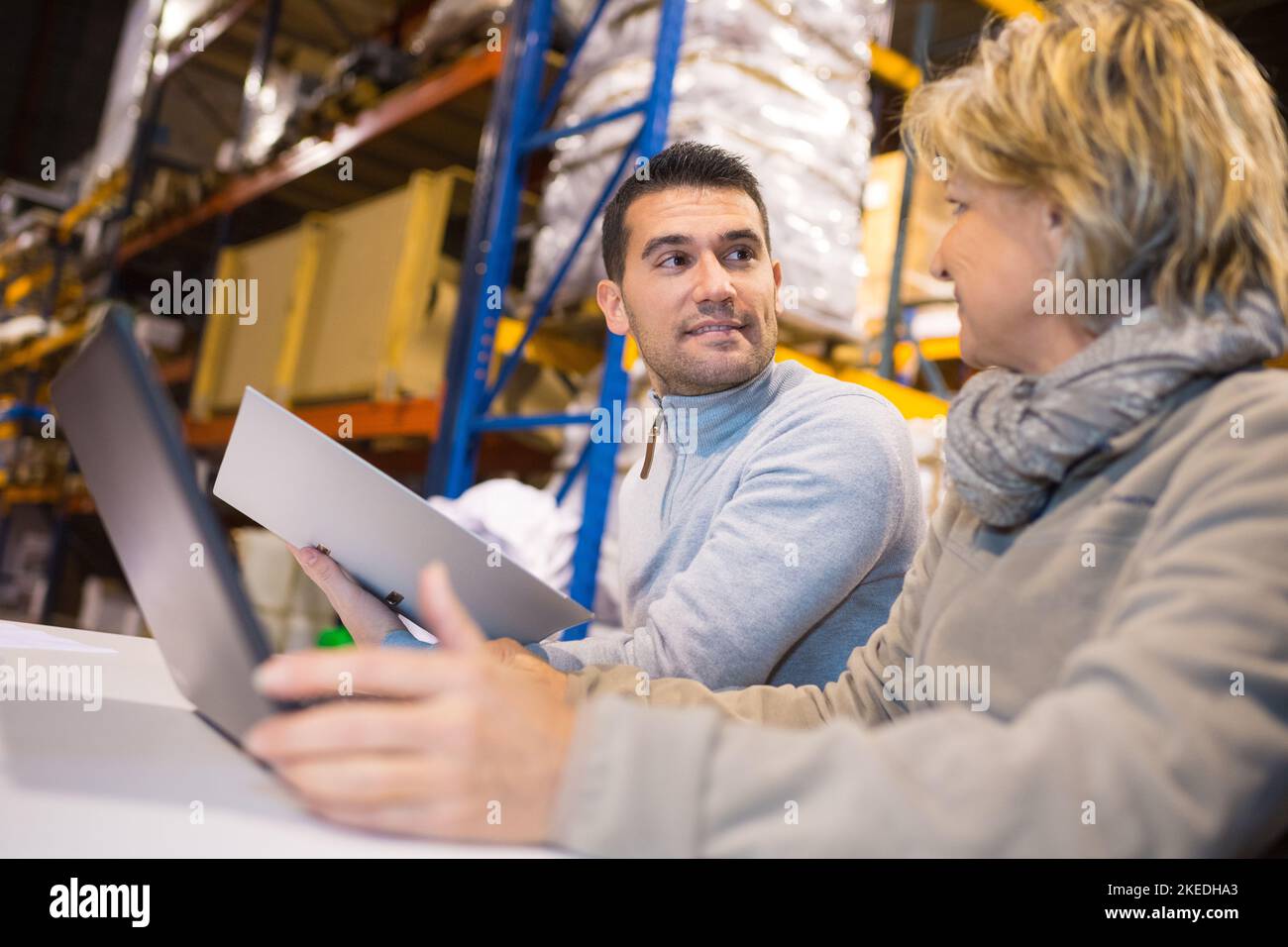 warehouse workers in discussion with laptop and folder Stock Photo - Alamy