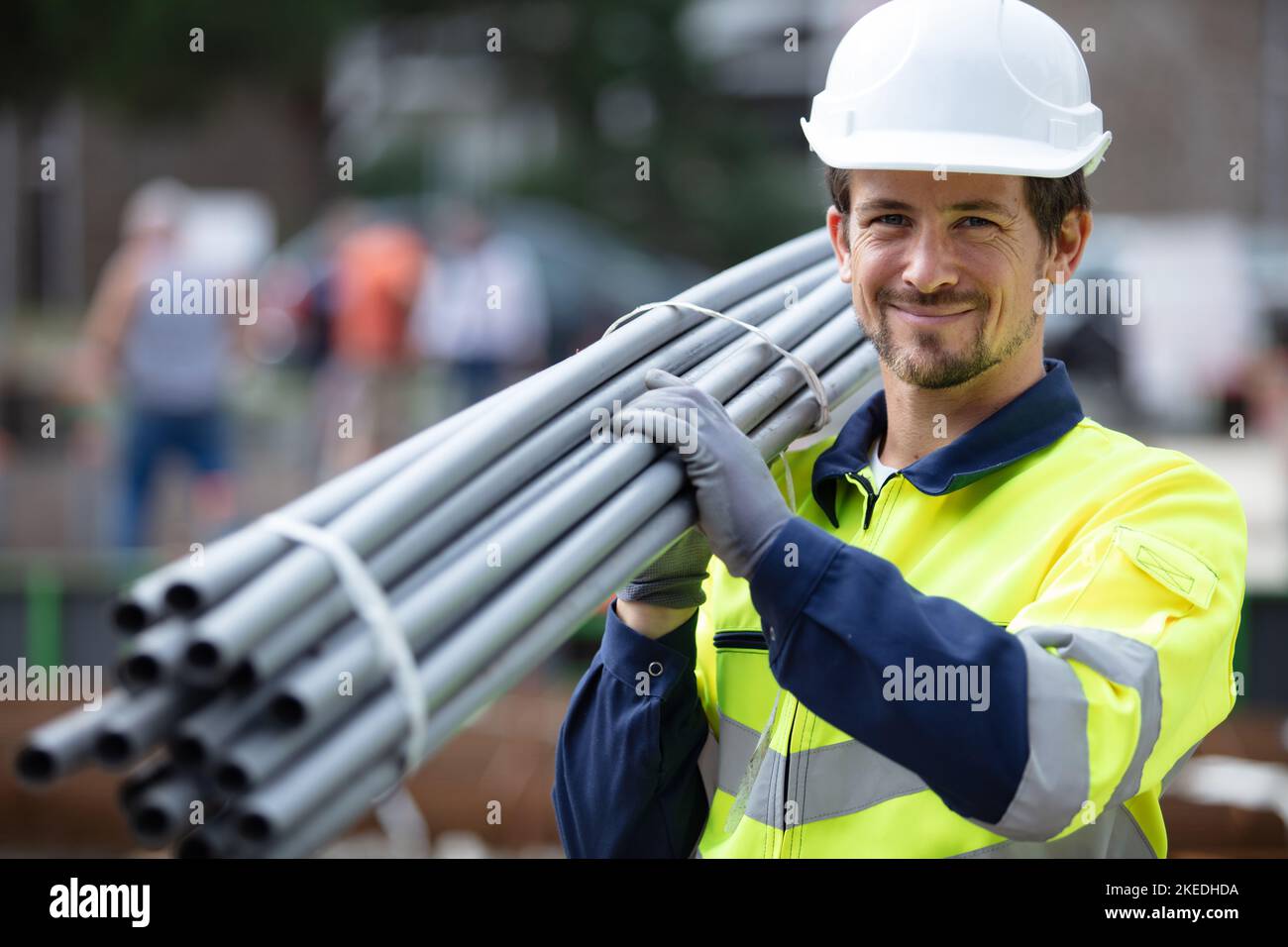 worker carries bundle of pipes on his shoulder Stock Photo - Alamy
