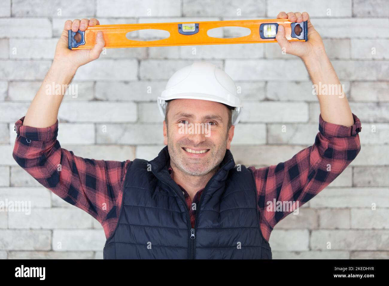 male builder holds a spirit level above his head Stock Photo - Alamy